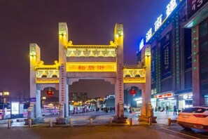 Um grande arco iluminado, com elementos arquitetônicos tradicionais, provavelmente servindo como portal ou entrada para um espaço público.