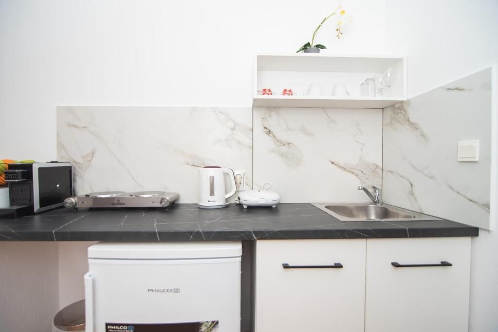 Cozinha moderna com painel de mármore, pia embutida e máquina de lavar louça compacta.