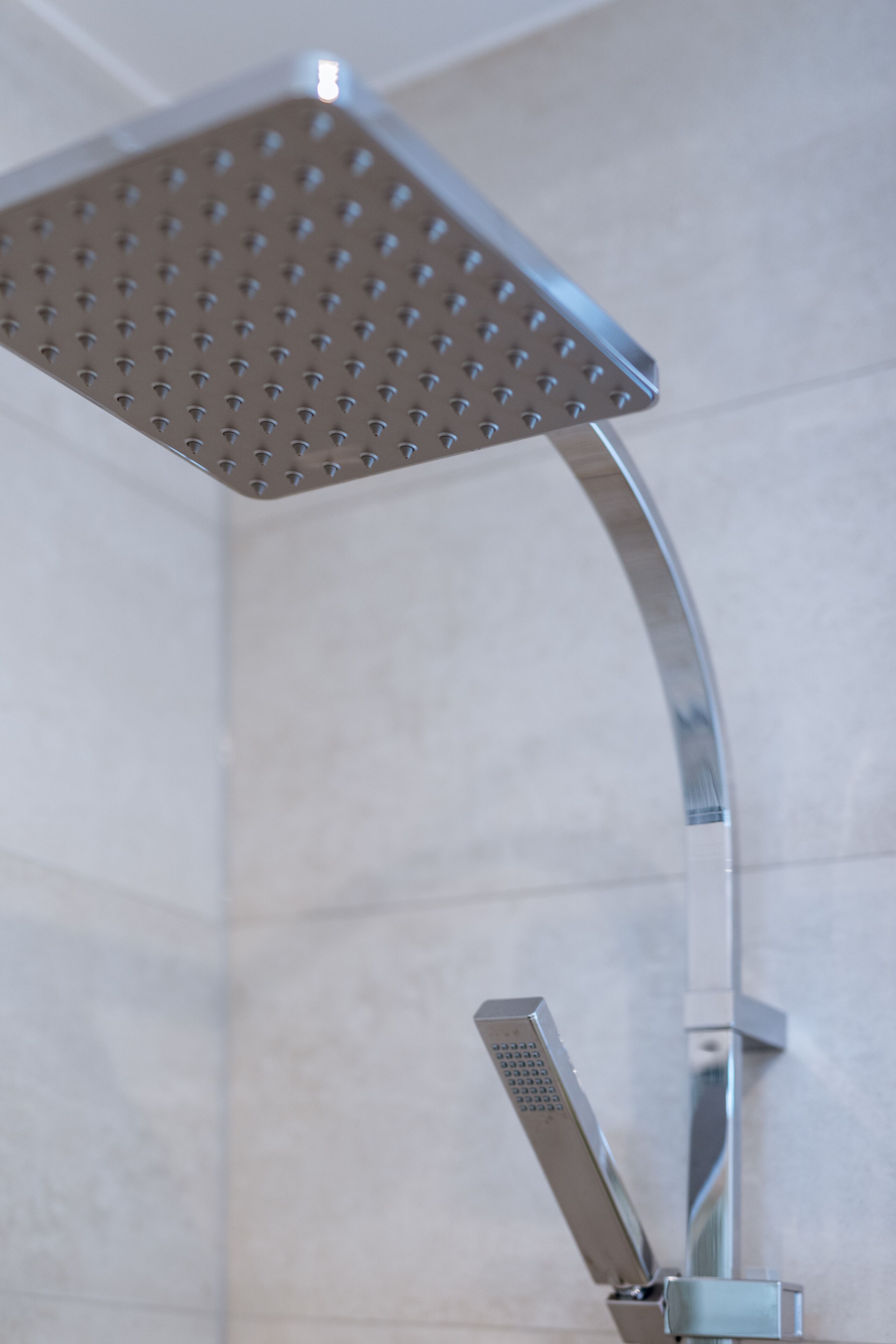 Chuveiro moderno com padrão de jato quadrado e um design de alça curvada.