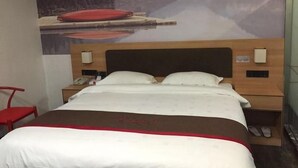 Quarto de hotel com cama, duas mesas de cabeceira, uma cadeira vermelha e um mural na parede com vista para um lago.
