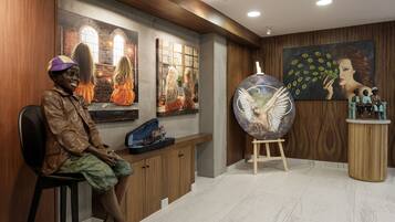 Quarto com um banco de madeira, um manequim e uma parede com obras de arte.