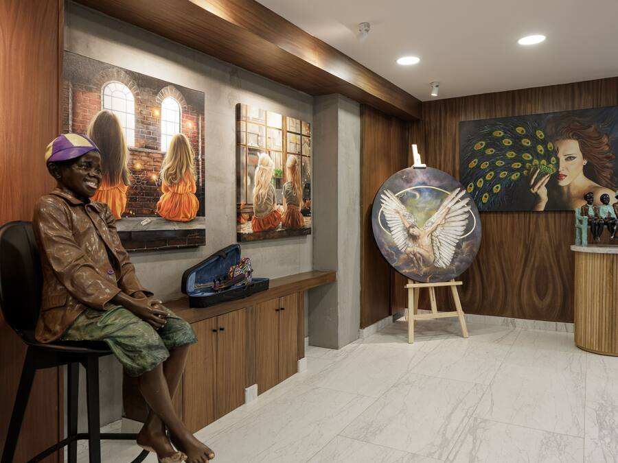 Quarto com um banco de madeira, um manequim e uma parede com obras de arte.
