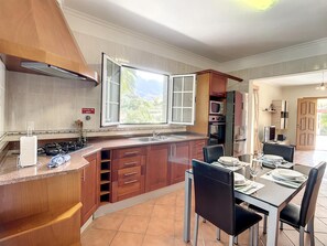 Uma cozinha moderna com armários de madeira, fogão a gás, micro-ondas e um espaço de refeições com cadeiras e mesa.