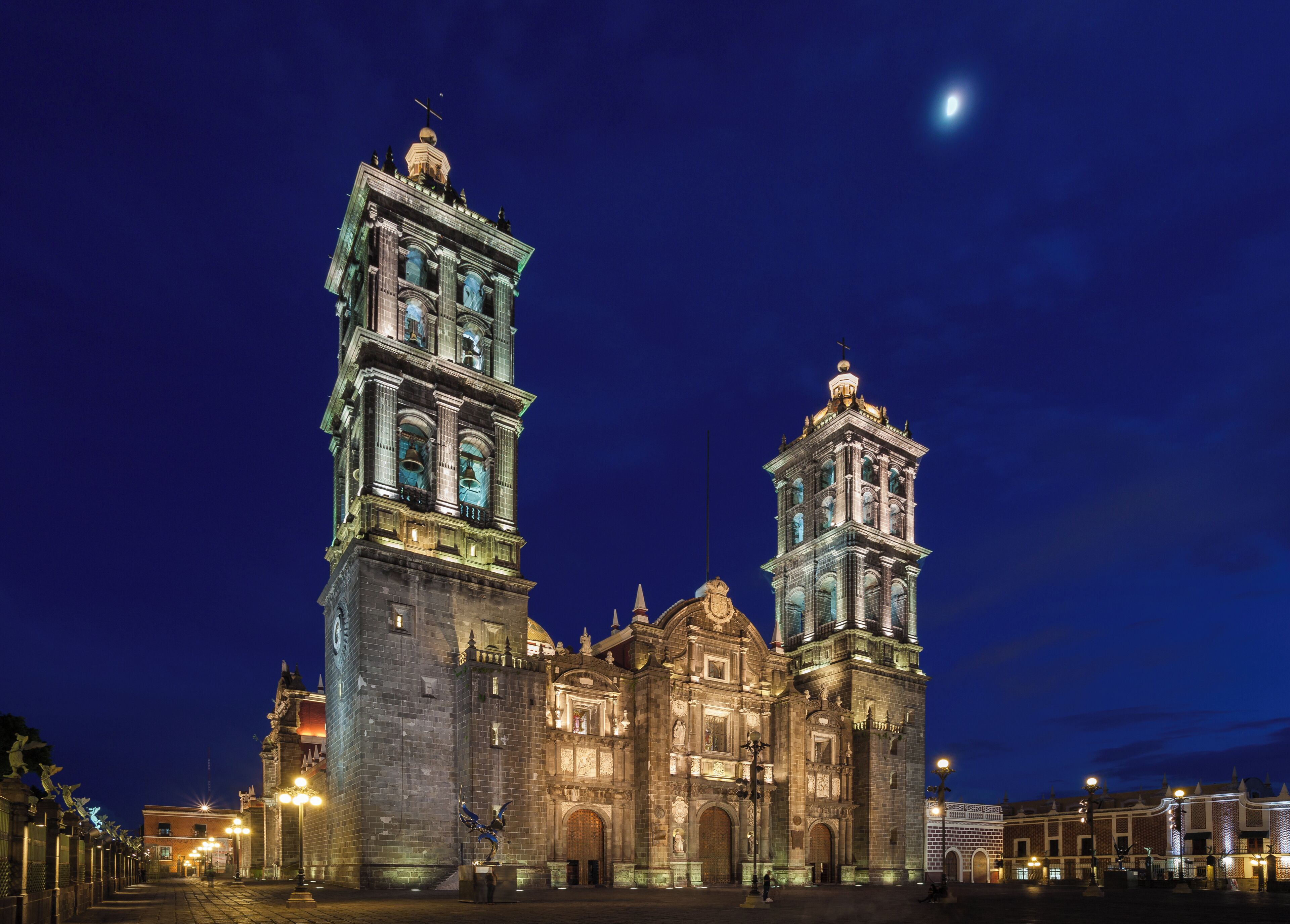 Um edifício histórico com duas torres imponentes e uma ampla entrada central, iluminado durante a noite.