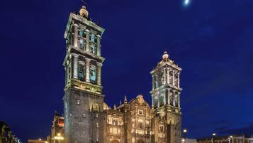 Um edifício histórico com duas torres imponentes e uma ampla entrada central, iluminado durante a noite.