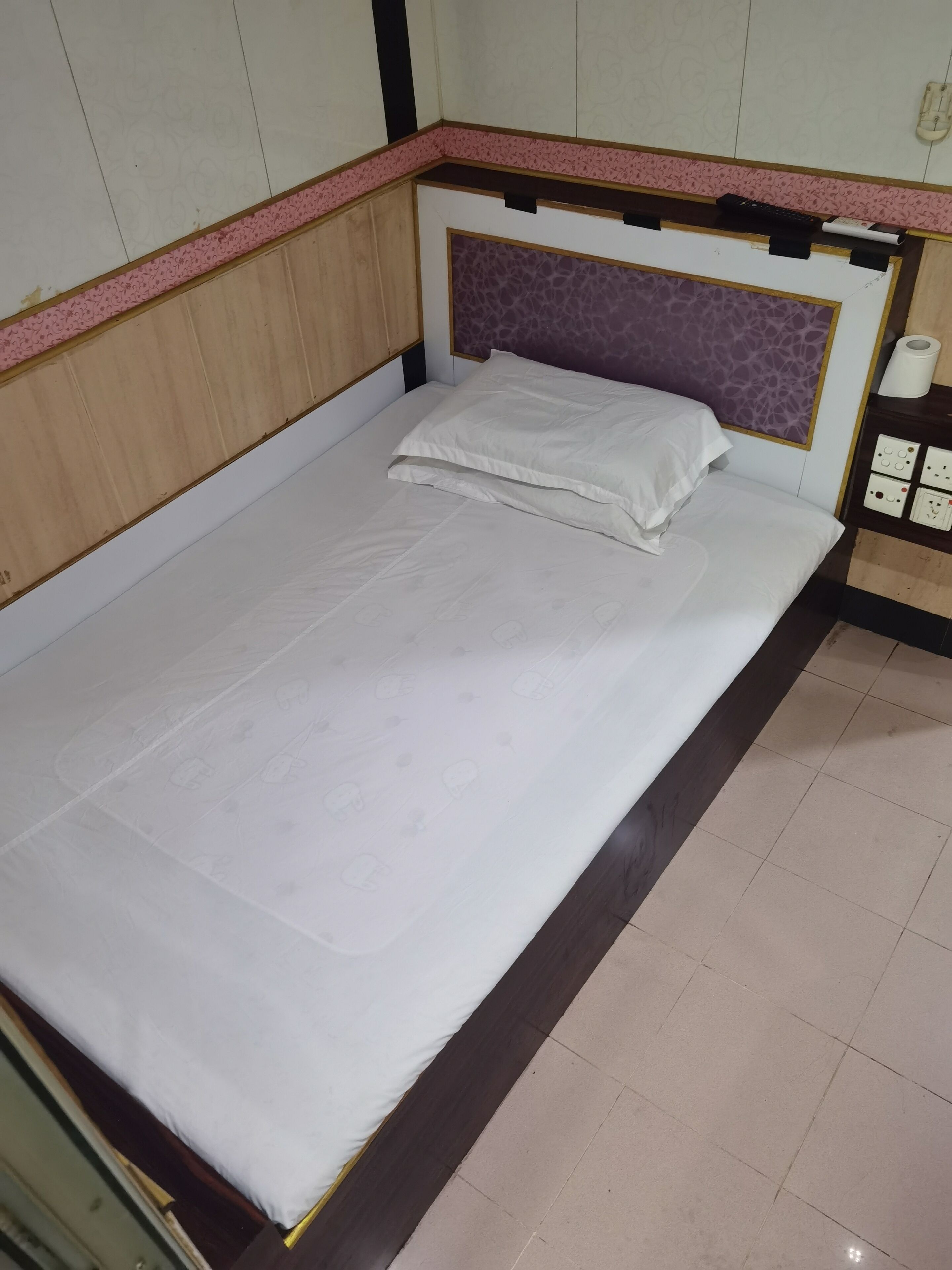 Uma cama de solteiro com cabeceira de madeira e colchão branco.