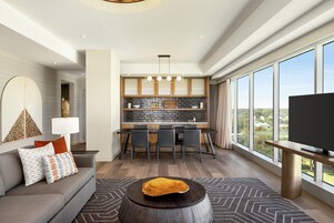 Uma sala de estar moderna com sofá, mesa de centro e televisão sobre um suporte.