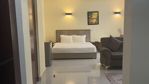 Quarto moderno com uma cama grande, um sofá e duas luminárias fixadas na parede.