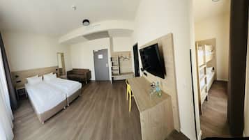 Quarto de hotel com duas camas, televisão, escrivaninha e uma cadeira.