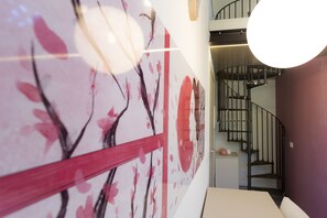 Uma escadaria com design moderno, uma parede com um mural floral e uma luminária redonda.