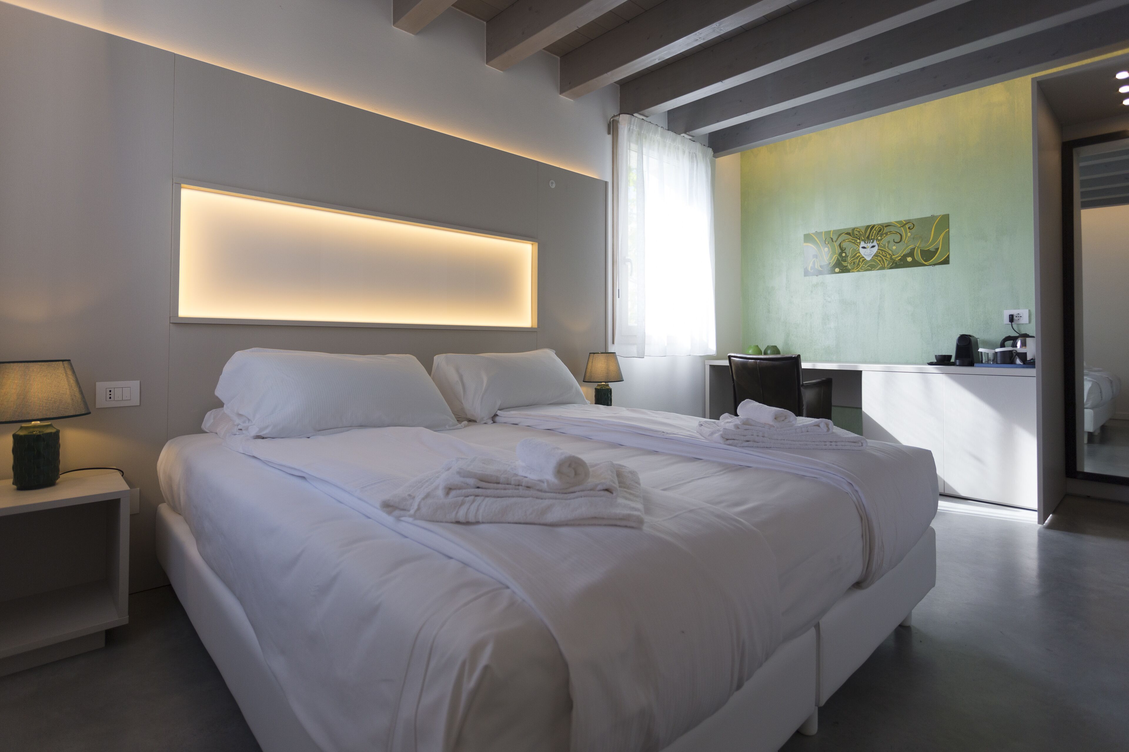 Quarto de hotel moderno com uma cama grande, abajures e vista para o banheiro.