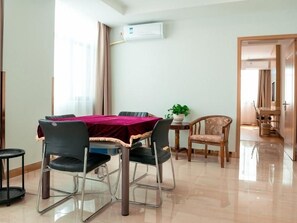 Uma sala de jantar com mesa e cadeiras, um vaso de planta e vista para um corredor.