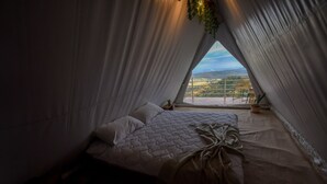 Quarto aconchegante em formato triangular, com uma janela grande que oferece uma vista panorâmica.