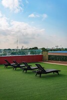 Uma área de lounge no terraço, com quatro espreguiçadeiras e guarda-corpo de vidro.