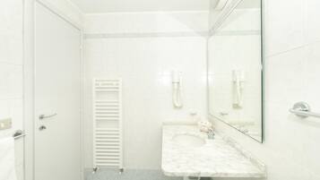 Casa de banho com uma pia branca, um espelho e um porta-toalhas.