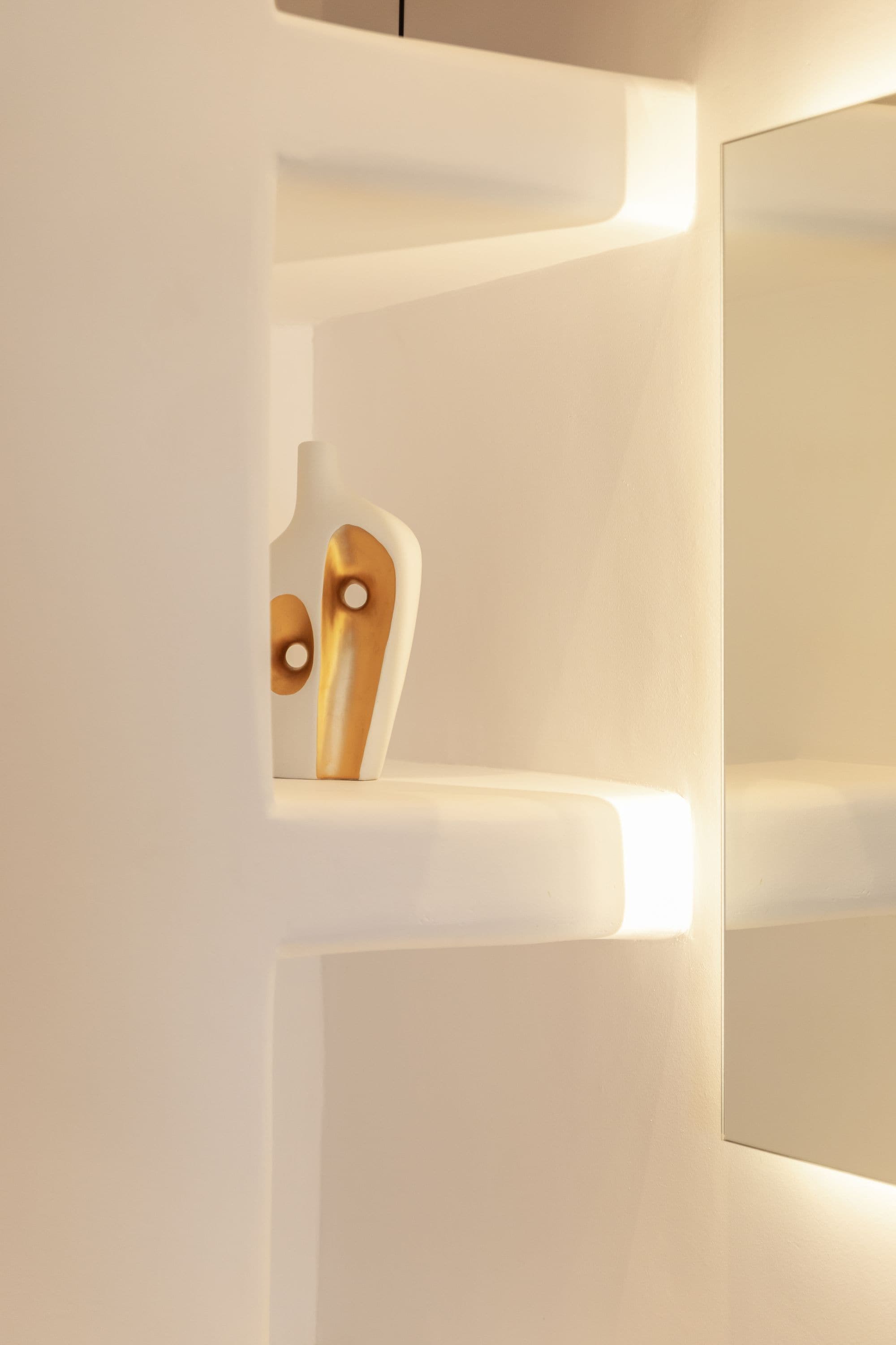 Um interior moderno com linhas limpas e design minimalista, apresentando uma parede branca e uma superfície refletora.