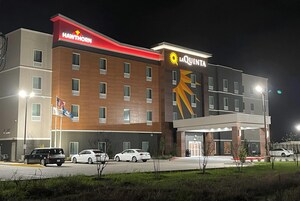 Um hotel com vários andares, com um toldo vermelho identificado como 'HAWTHORN' e um toldo amarelo identificado como 'LA QUINTA'.