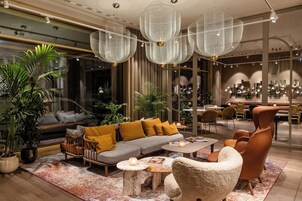 Um interior moderno com um sofá cinzento, poltronas laranja e uma mesa de centro.