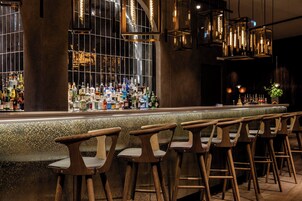 Uma área de bar com um balcão comprido, vários bancos e uma variedade de garrafas.