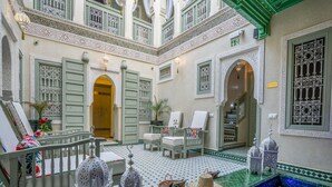 Um pátio com piscina, área de estar e detalhes arquitetônicos elaborados.