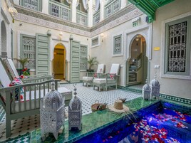 Um pátio com piscina, área de estar e detalhes arquitetônicos elaborados.