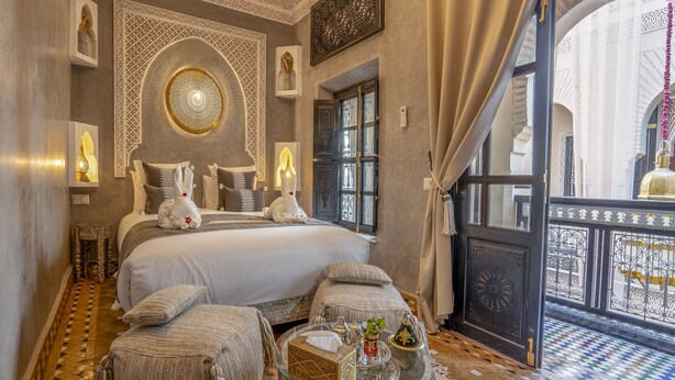 Quarto luxuoso com uma cama grande, decorações de parede elaboradas e uma varanda com vista.