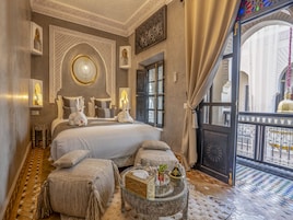 Quarto luxuoso com uma cama grande, decorações de parede elaboradas e uma varanda com vista.