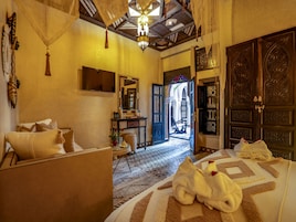 Quarto tradicional marroquino com uma cama, uma escrivaninha e um espelho.