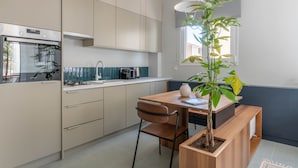 Uma cozinha moderna com uma mesa de jantar de madeira, uma cadeira e um vaso com planta.