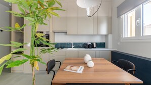 Uma cozinha moderna com uma mesa de madeira, duas cadeiras, uma planta em vaso e uma revista.