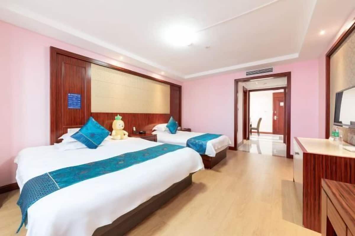 Quarto de hotel com duas camas, uma escrivaninha e um espelho.