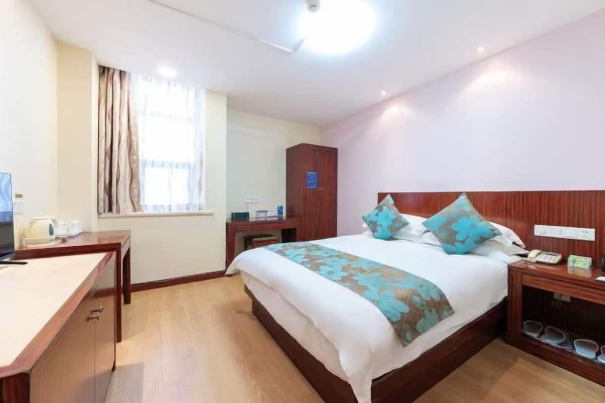 Quarto de hotel com uma cama, mesa de cabeceira e escrivaninha com cadeira.