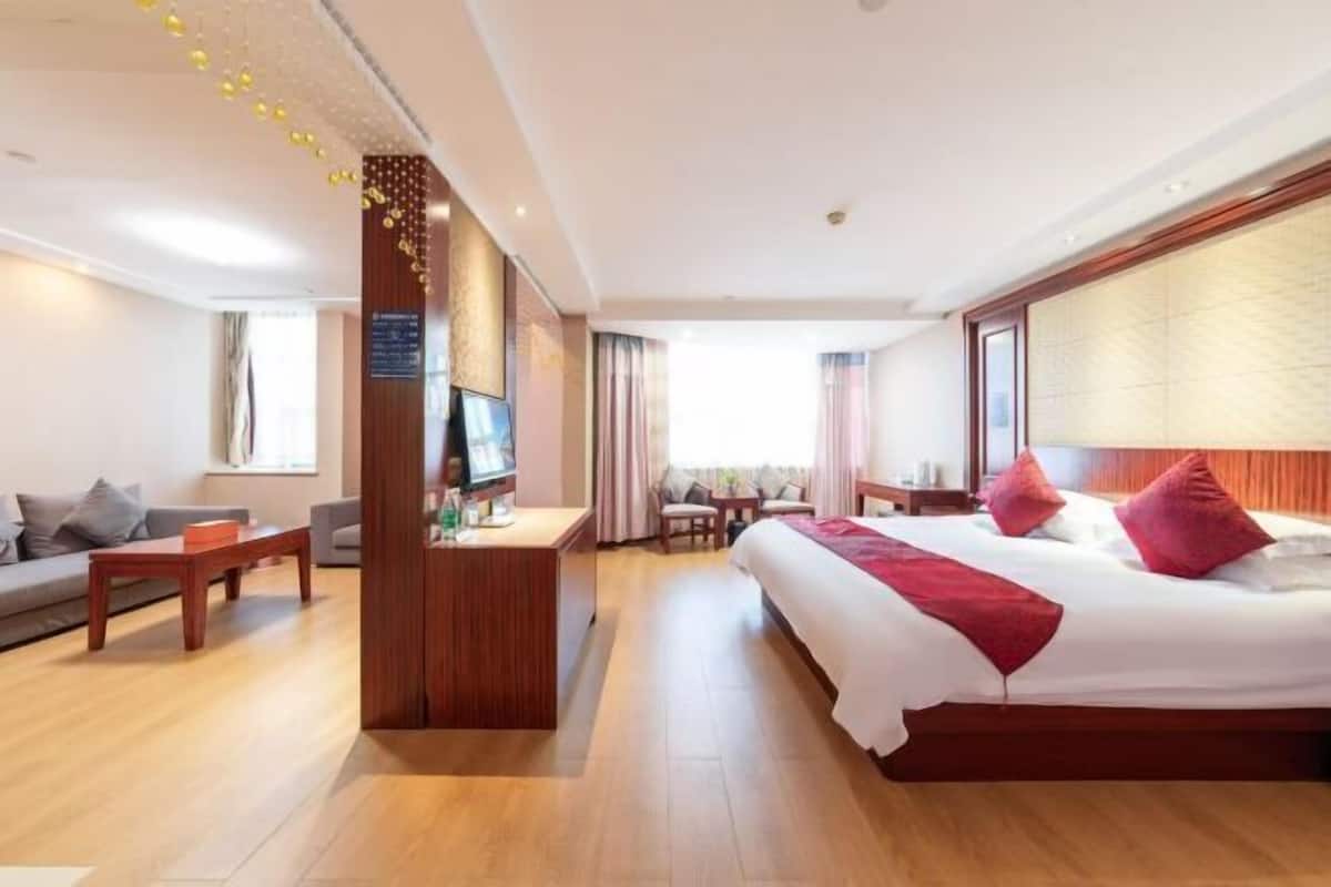 Quarto de hotel com uma cama grande, uma escrivaninha, um sofá e uma televisão.