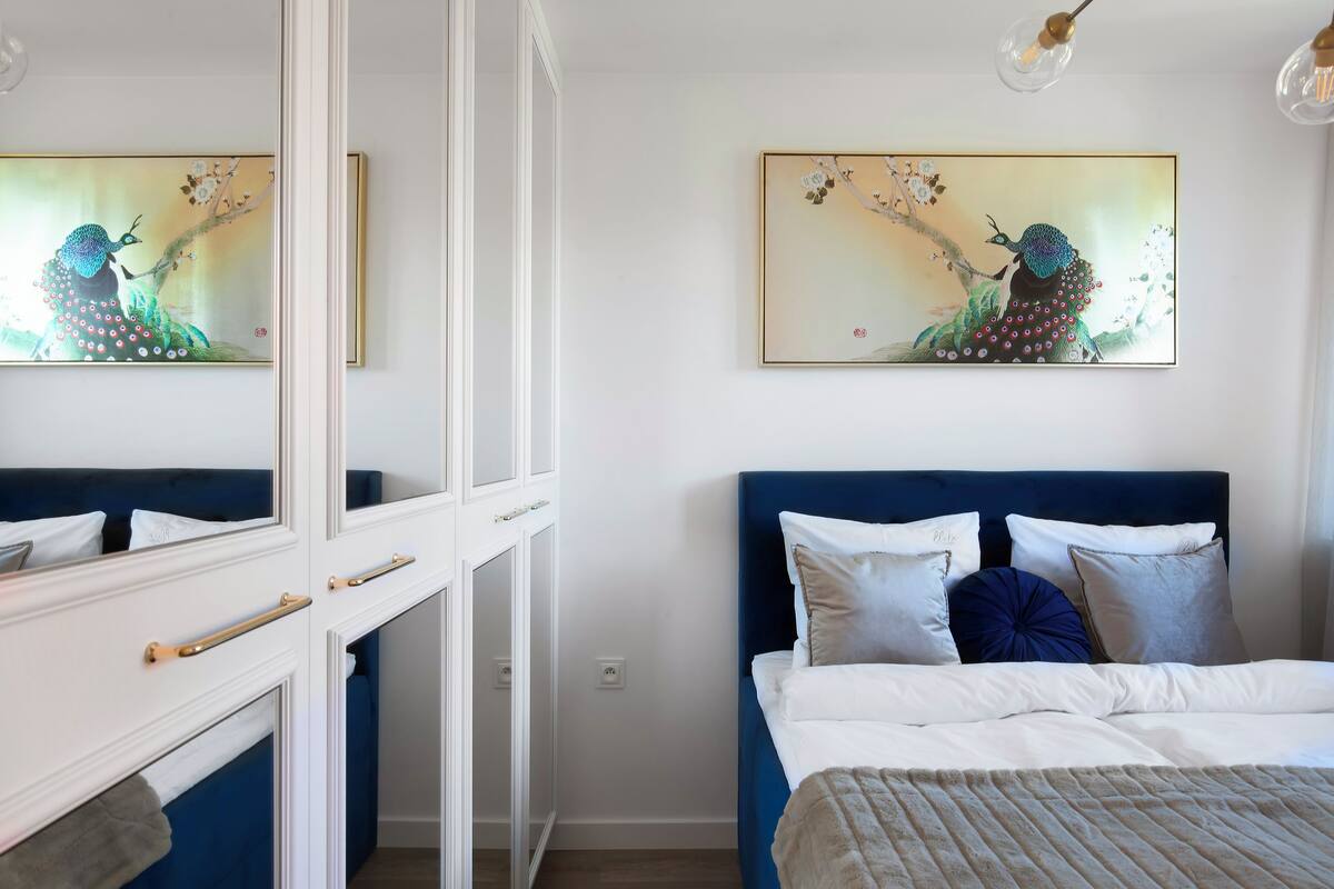 Quarto com cama, almofadas, mesa de cabeceira e espelho.