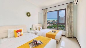 Quarto de hotel com duas camas, uma janela grande com vista, uma luminária no teto e um ar condicionado.