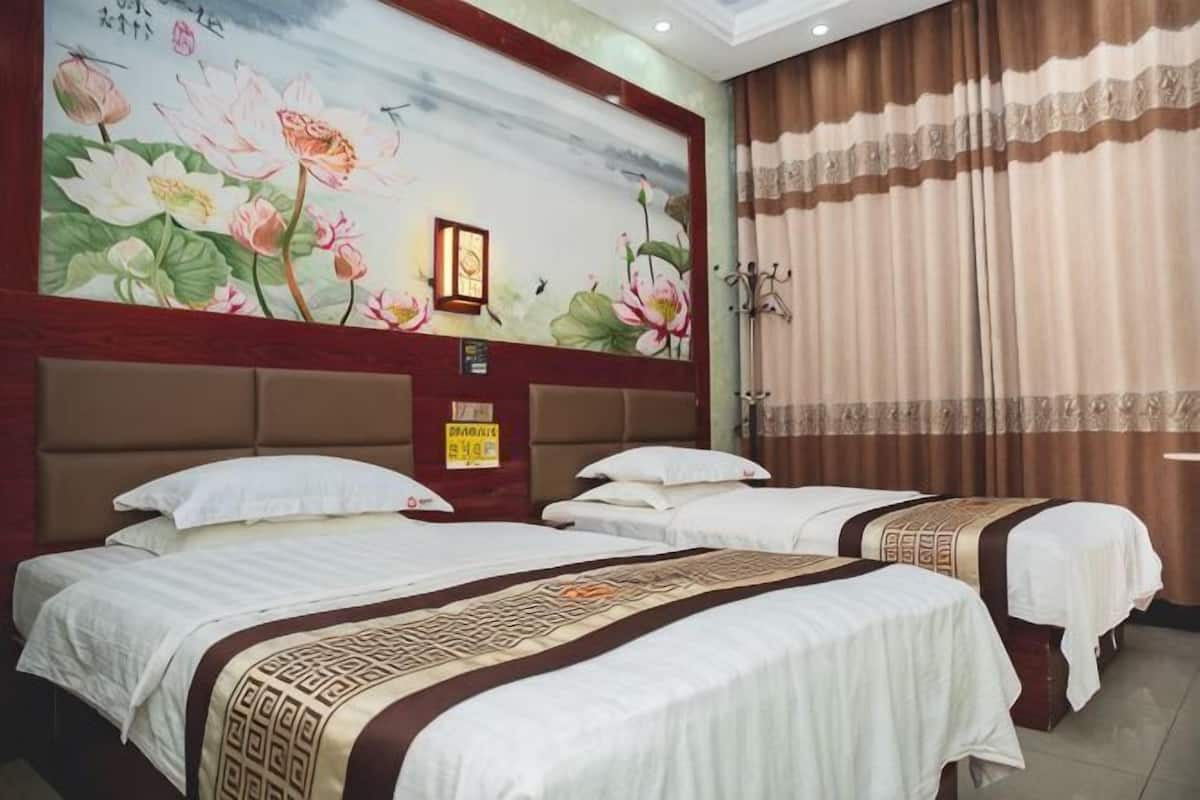 Quarto de hotel com duas camas, um mural de flores na parede e uma cortina estampada.