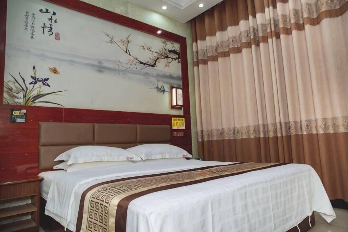 Quarto de hotel com uma cama, parede decorada, cortinas e uma placa na parede.