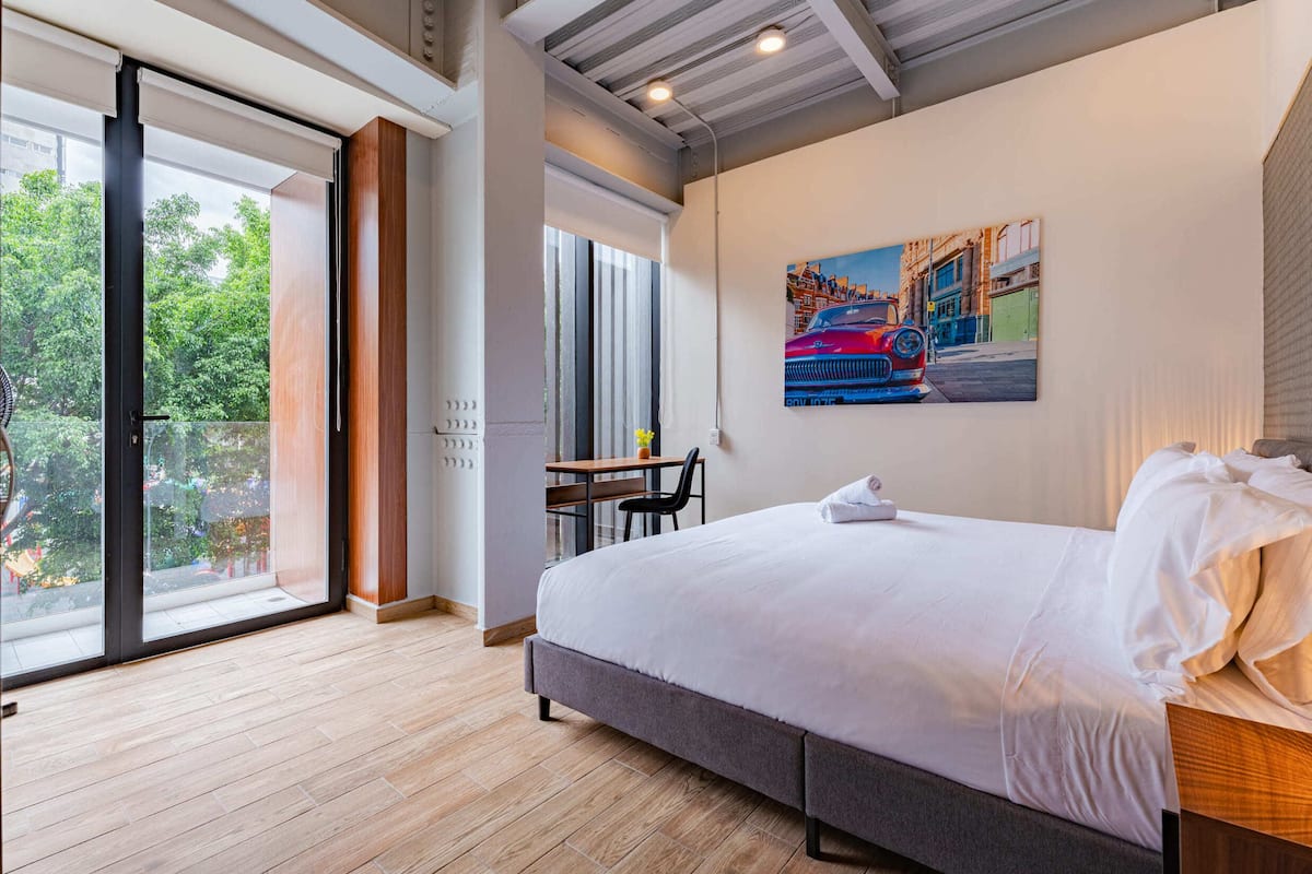 Um quarto moderno com uma cama grande, uma escrivaninha e um quadro na parede.