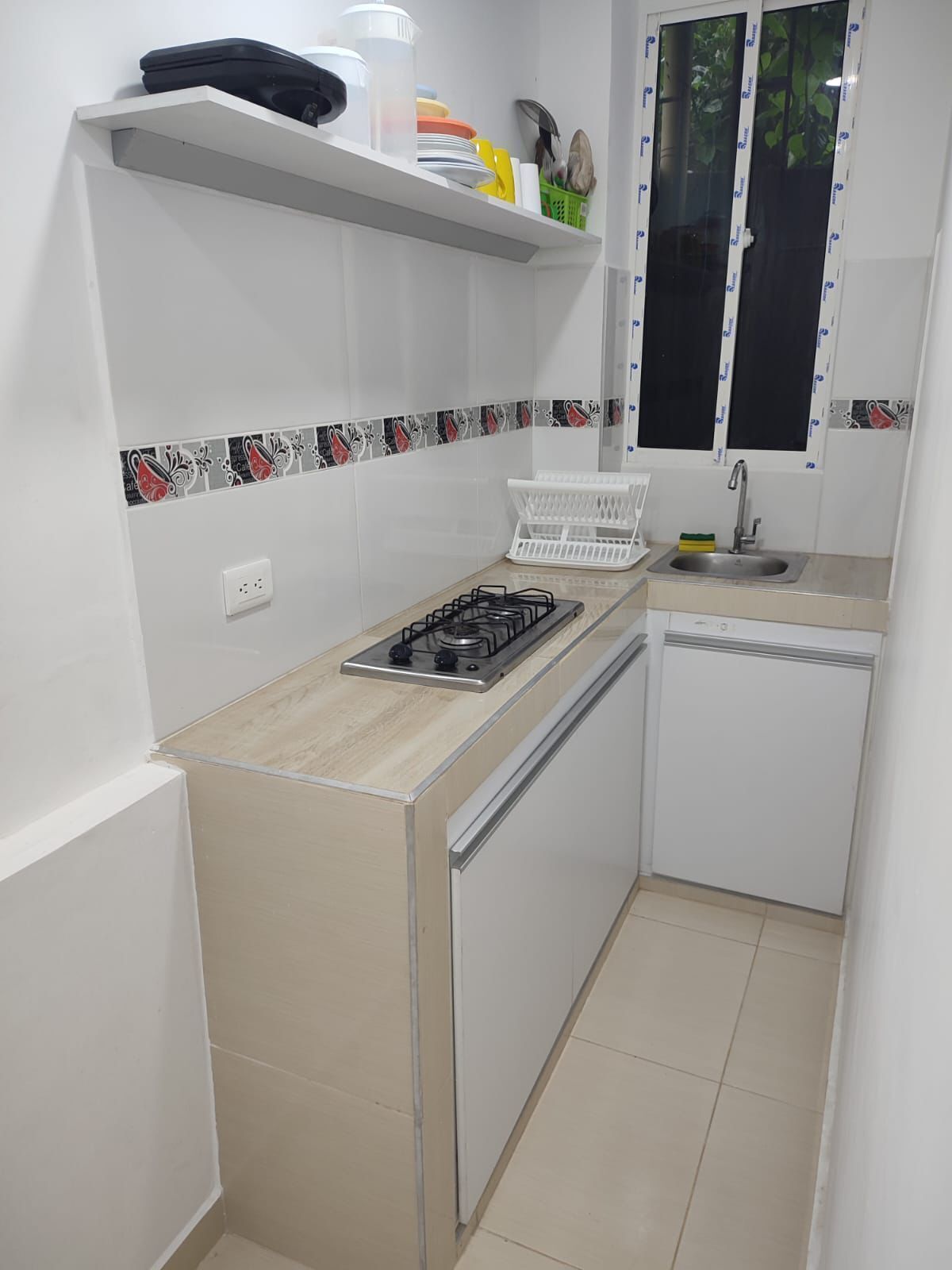 Cozinha compacta com fogão a gás, pia e bancada pequena.