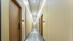 Um corredor comprido e estreito, com portas de madeira em ambos os lados e um chão brilhante e refletor.