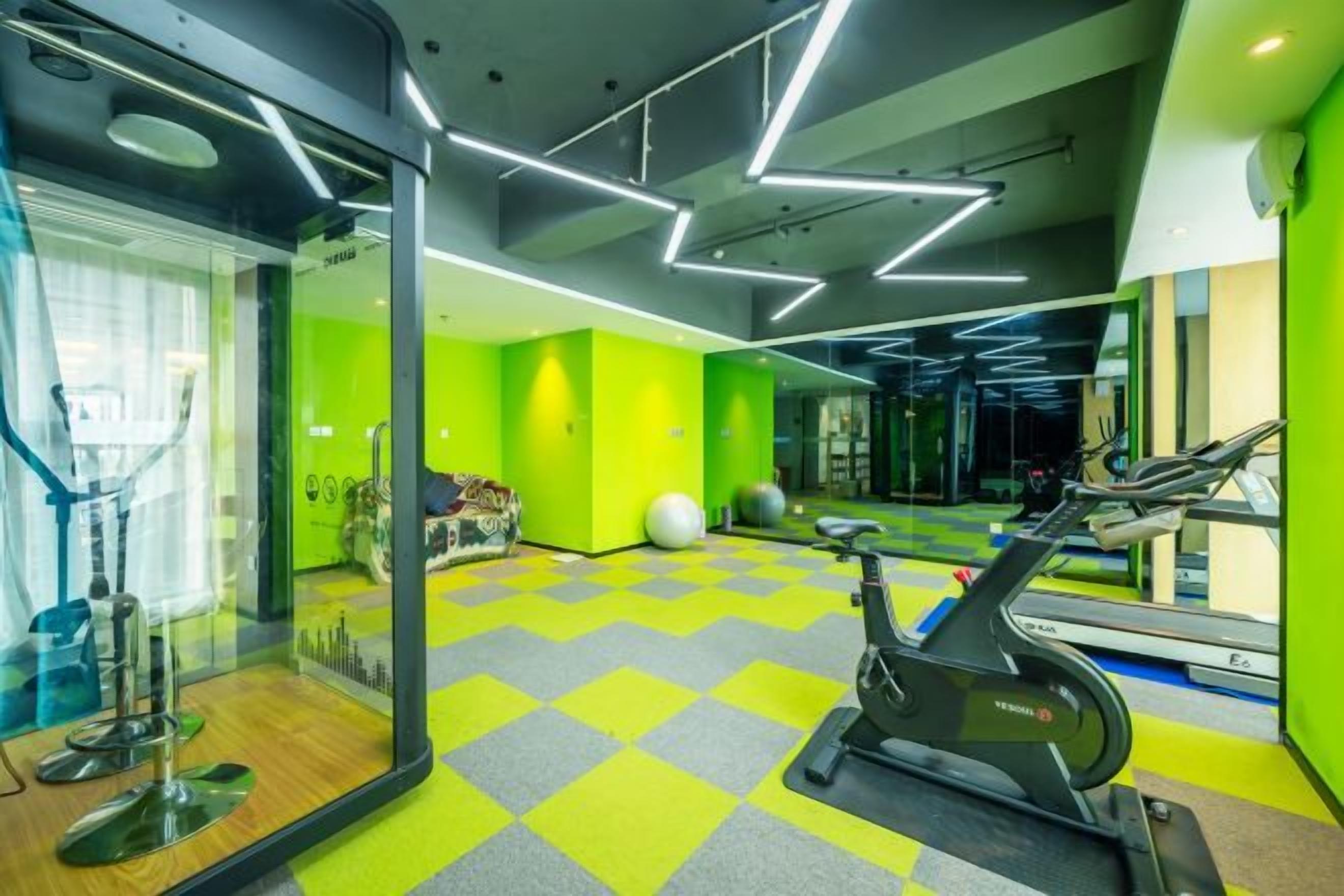 Academia com equipamentos de ginástica, um espelho e piso xadrez.