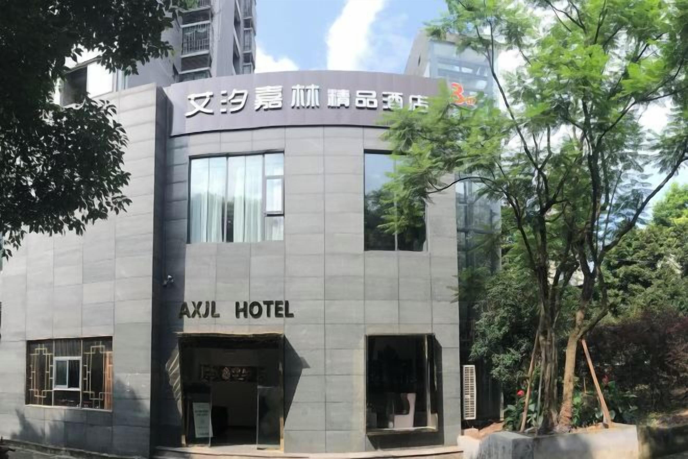 Um hotel com fachada moderna, placas indicando ser o AXJL Hotel e uma entrada visível.