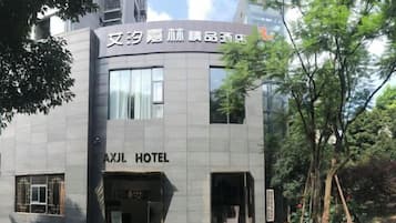 Um hotel com fachada moderna, placas indicando ser o AXJL Hotel e uma entrada visível.