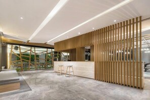 Uma área de recepção moderna com divisória de madeira, balcão de atendimento e espaço de espera com bancos.