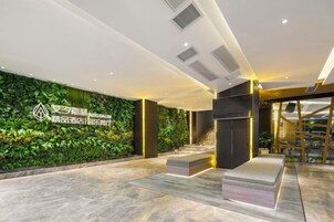 Um hall de hotel com parede verde, balcão de recepção e escada.