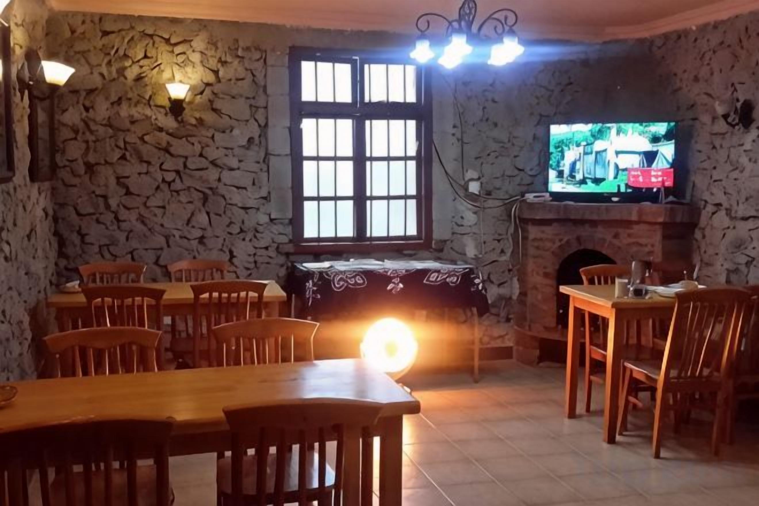 Espaço de refeições com paredes de pedra, lareira e televisão.