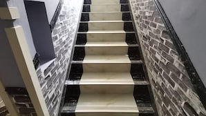 Uma escadaria com ladrilhos pretos e brancos alternados, que dá acesso a um andar superior.