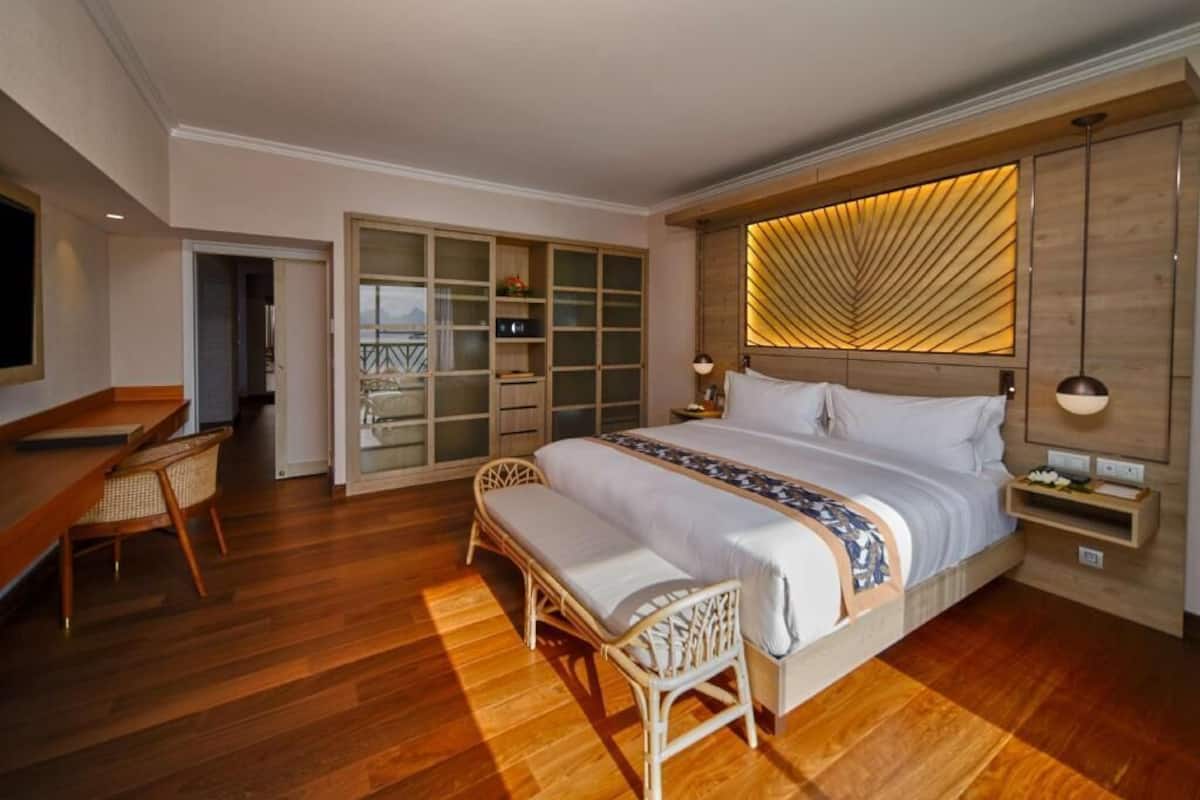 Quarto com uma cama grande, uma escrivaninha, uma cadeira, um guarda-roupa e vista através de uma porta de vidro.