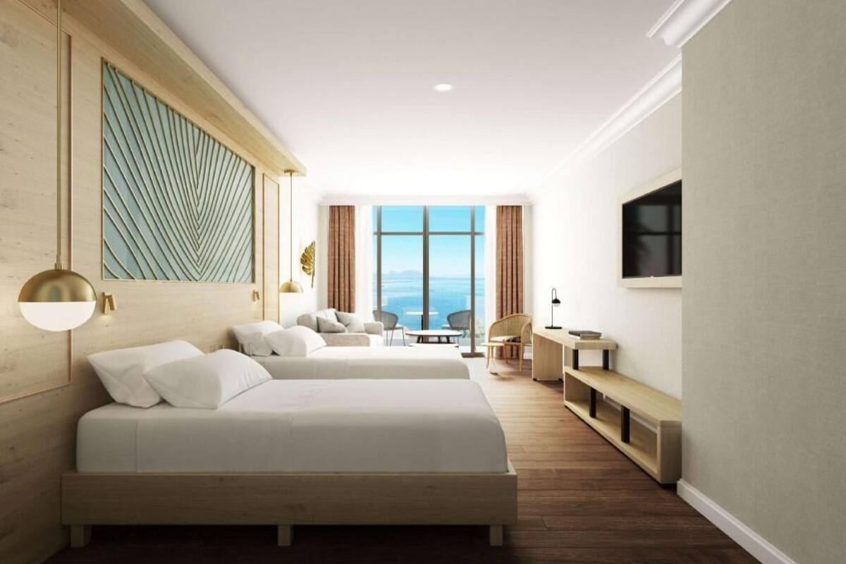 Quarto de hotel moderno com duas camas, uma janela grande com vista, uma mesa e uma cadeira.