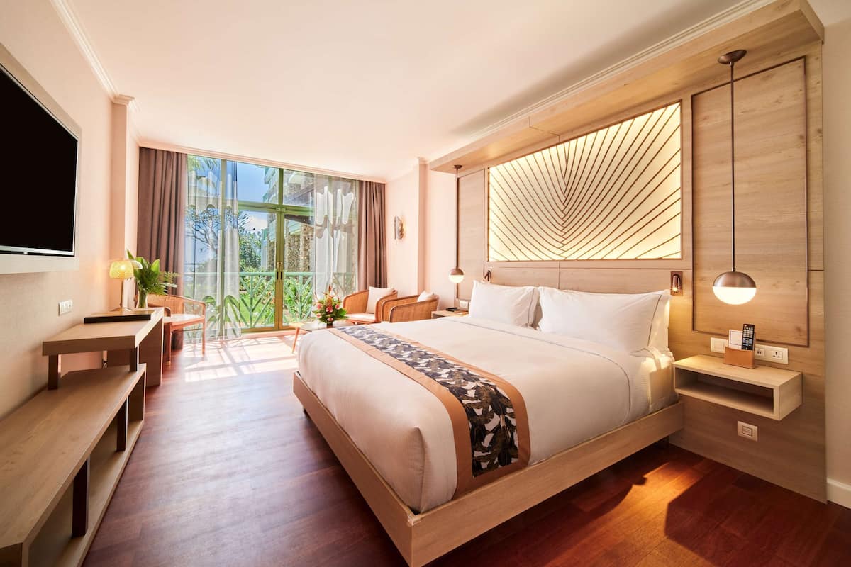 Quarto de hotel moderno com uma cama grande, uma mesa, uma cadeira, uma TV e uma varanda com vista.